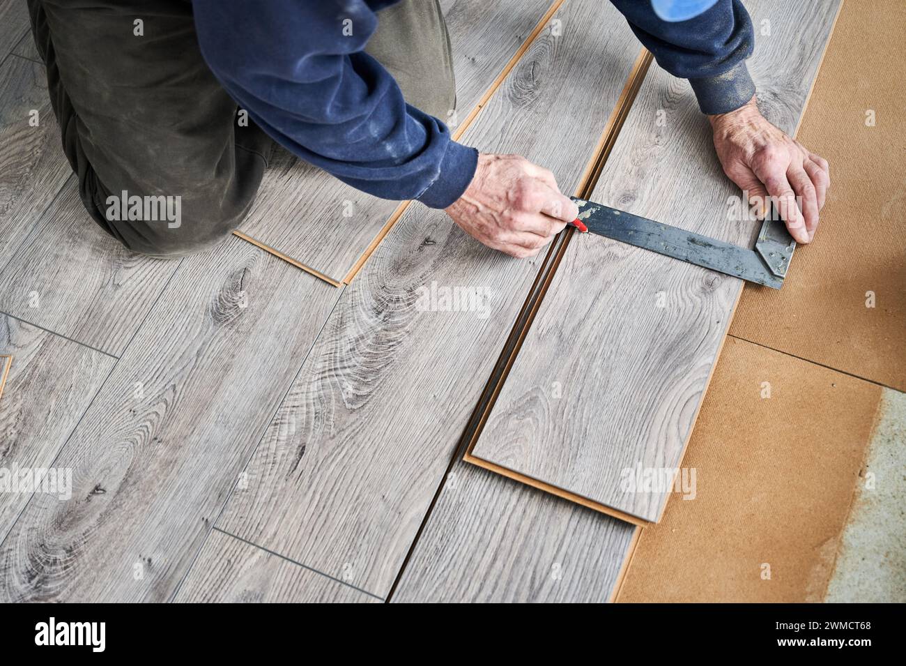 Close up of male construction worker using metal ruler and pencil while ...