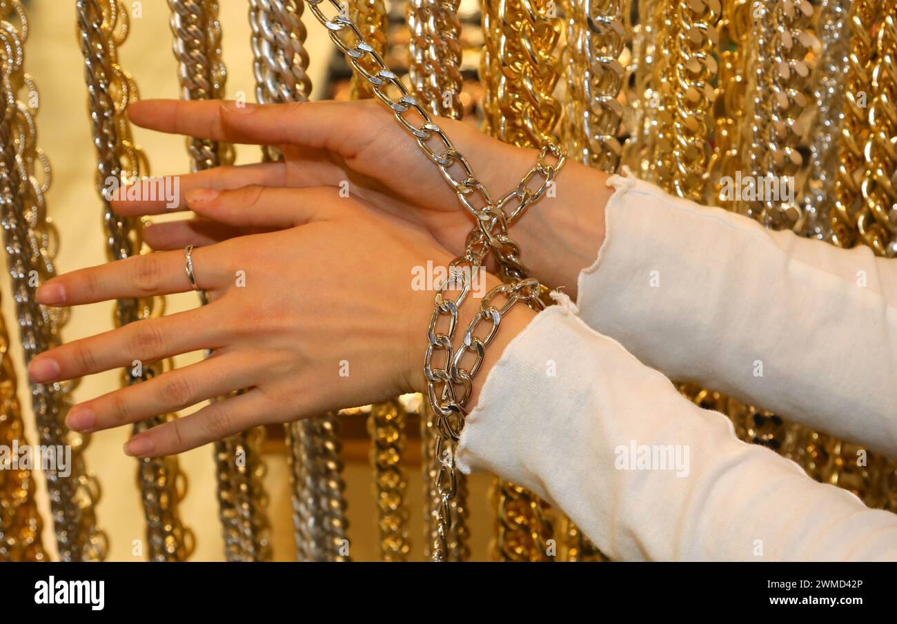Two hands of young girl chained the long metal chain on her slender ...