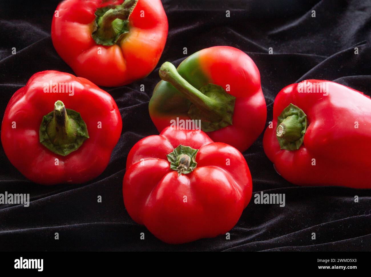 Bright red Bell peppers and kiwi fruits on black fabric. Fruit and ...