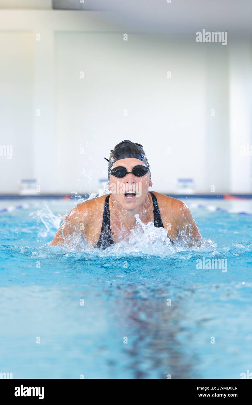 Caucasian female athlete swimmer swims vigorously in an indoor pool ...