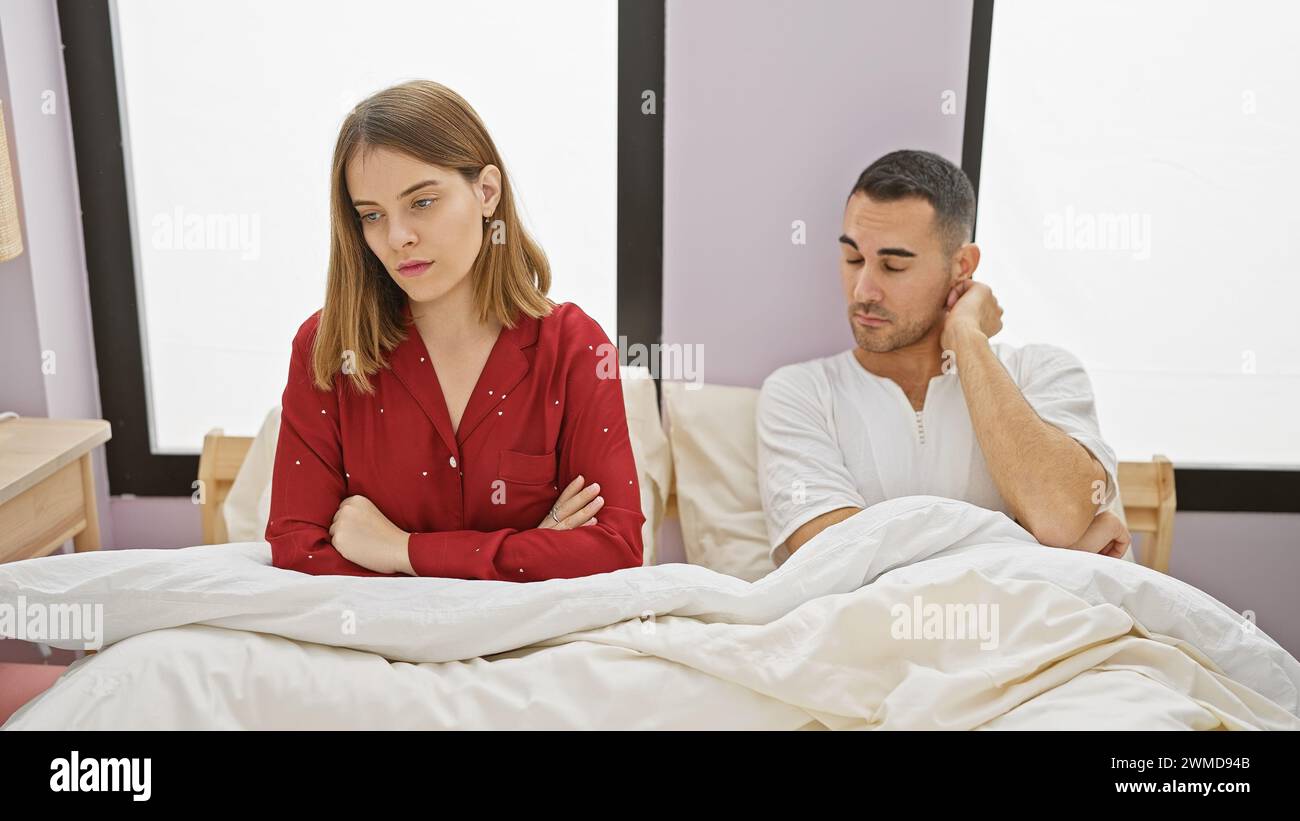 A discontented woman and a man sit apart in bed, symbolizing ...