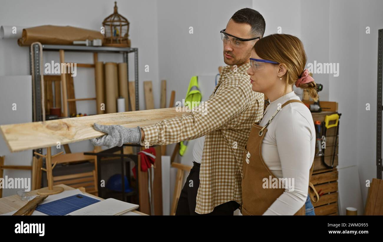 Man and woman carpenters examining a wooden plank in a well-equipped ...
