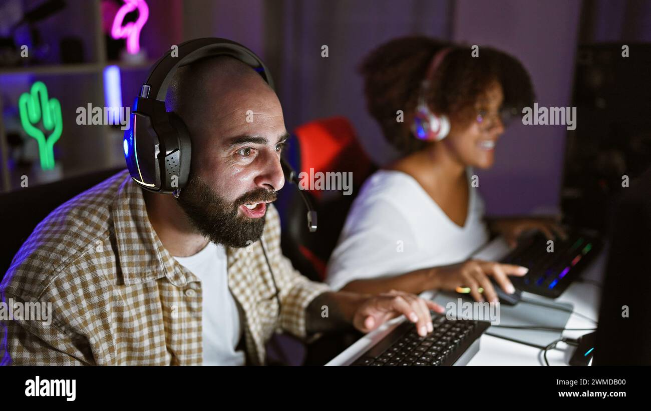 Two cheerful gamers, man and woman, smiling confidently while playing ...