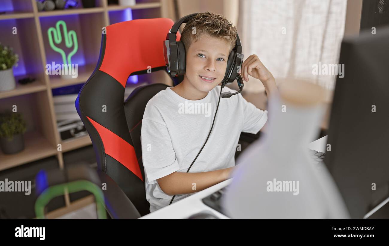 Adorable blond boy streamer happily playing gaming, streaming a video ...