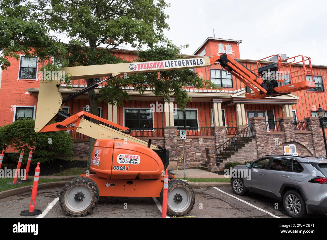Rental cherry picker boom lift parked in front of a building under ...