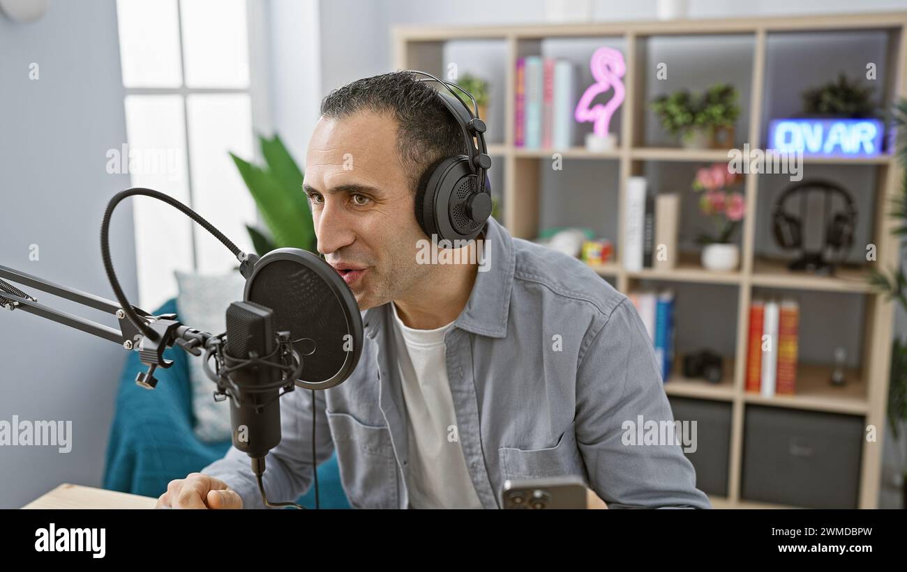 Handsome hispanic man speaking into microphone in a radio studio ...