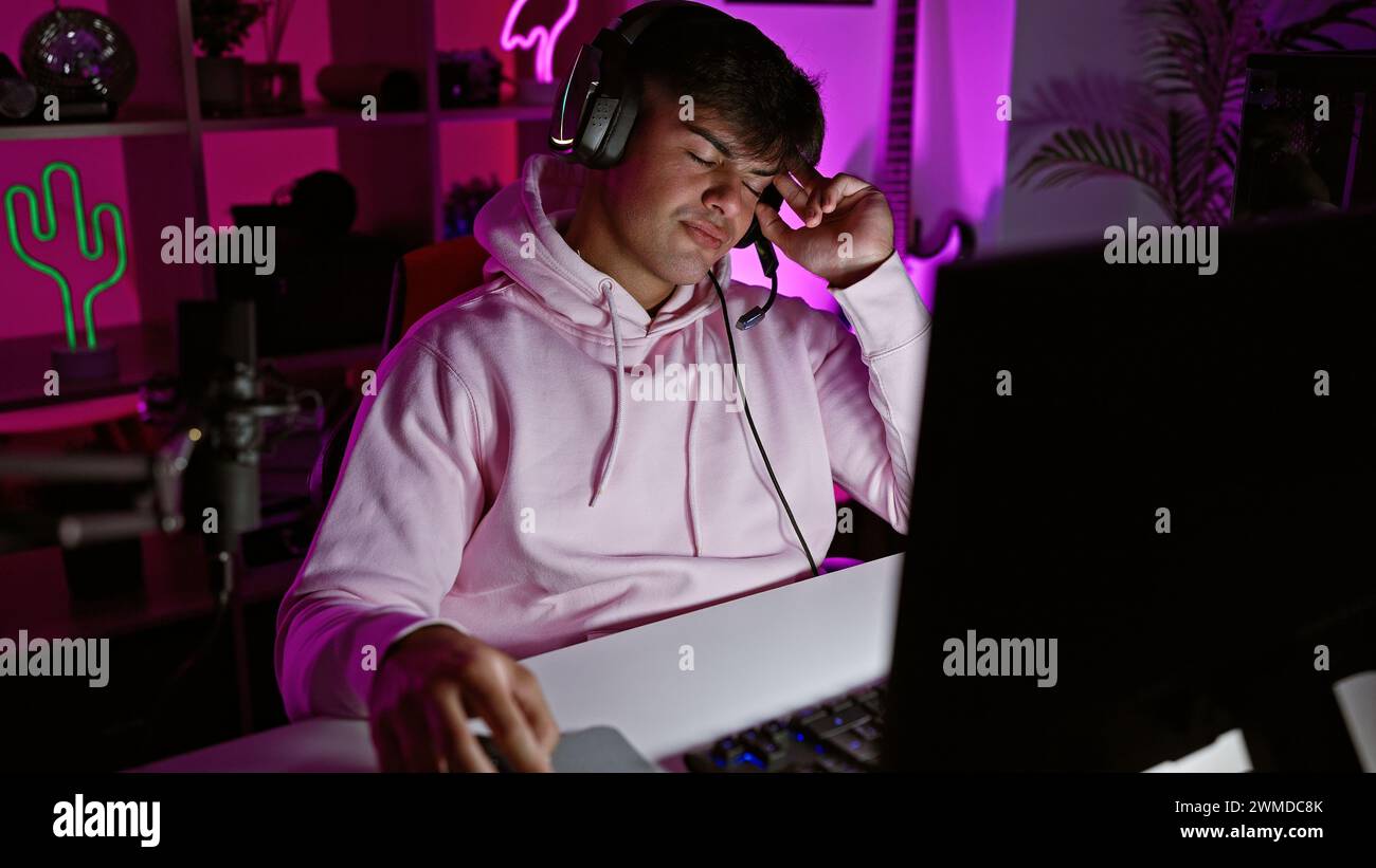 Tired young hispanic man streamer, late night gaming session in dark ...