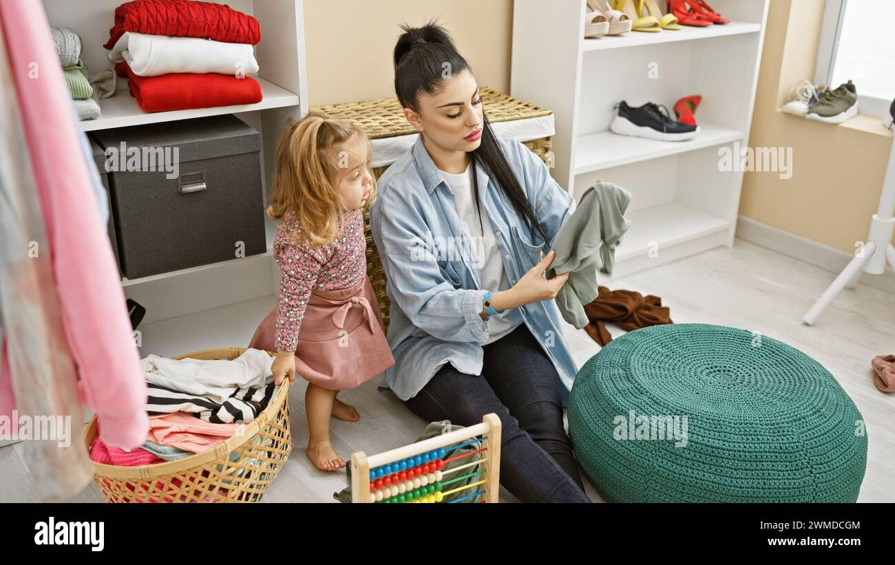Mother and daughter organizing wardrobe together in a bright room ...
