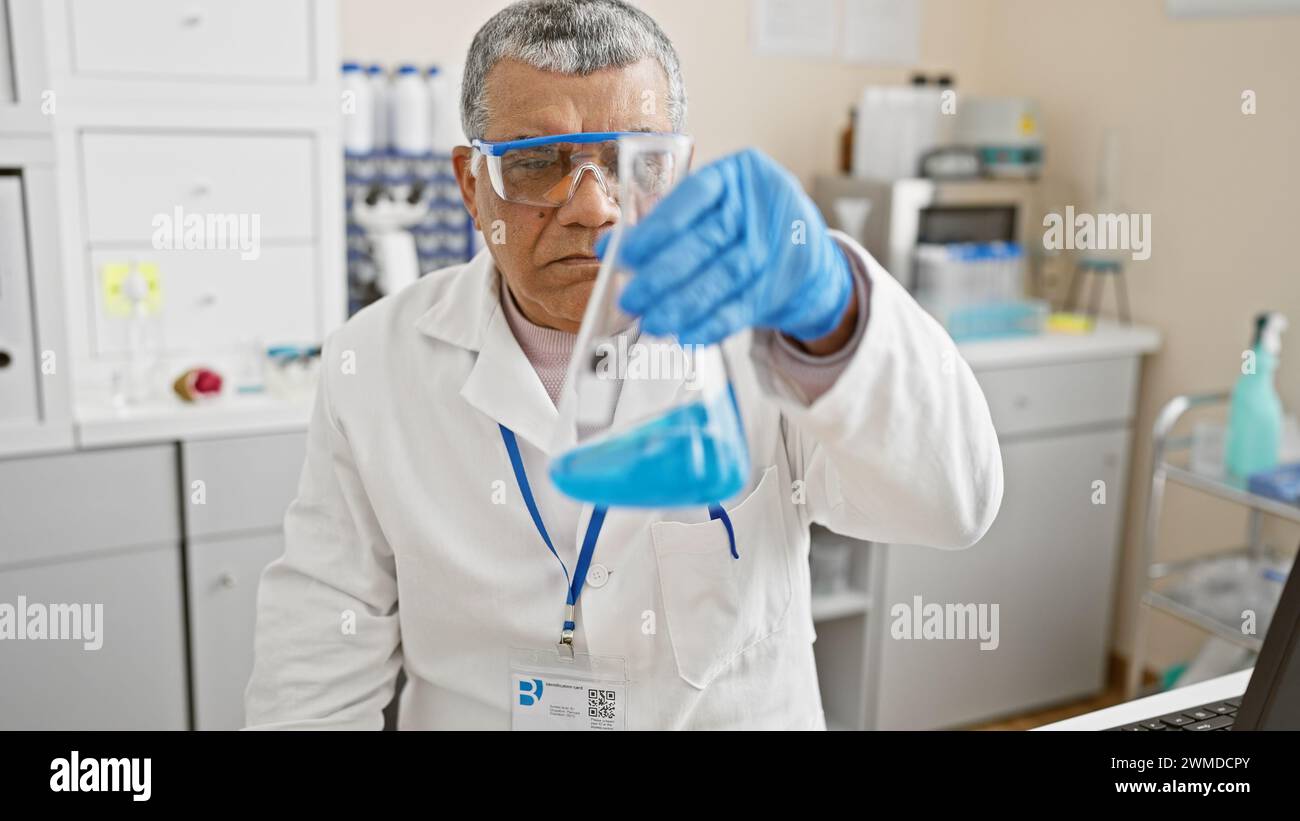 Middle-aged man in lab coat examines contents of a beaker in a ...