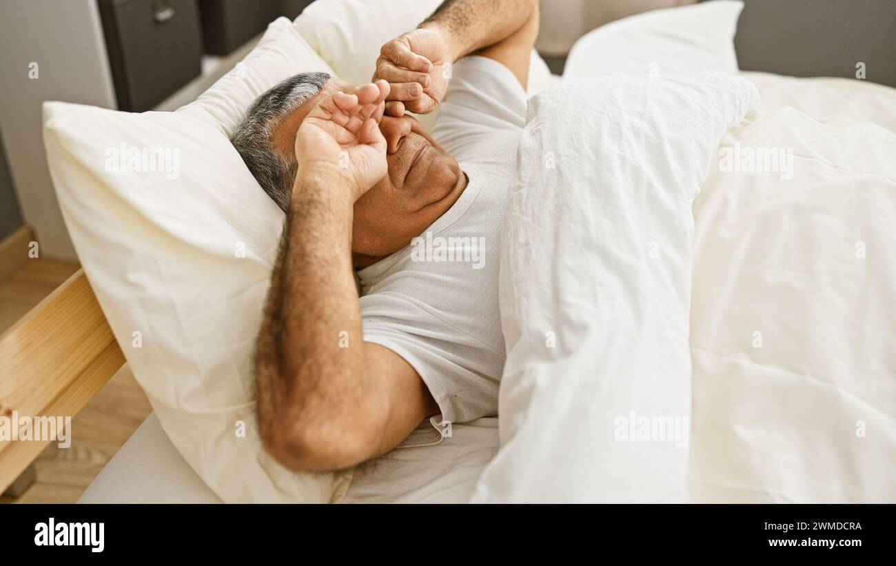 Mature Man Resting In Bedroom With White Bedding In A Modern Home