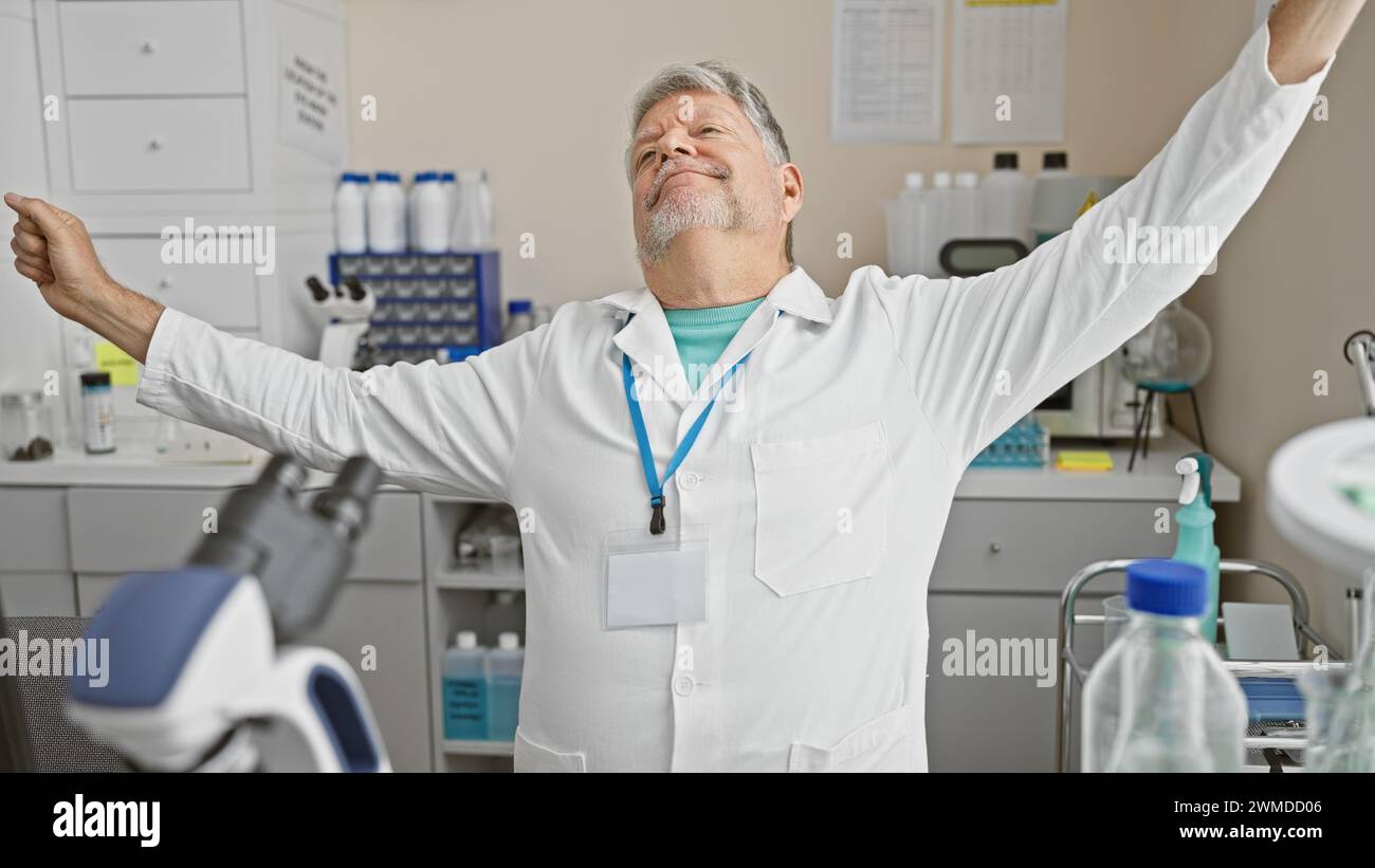 Middle-aged man in labcoat stretching in a laboratory, displaying ...