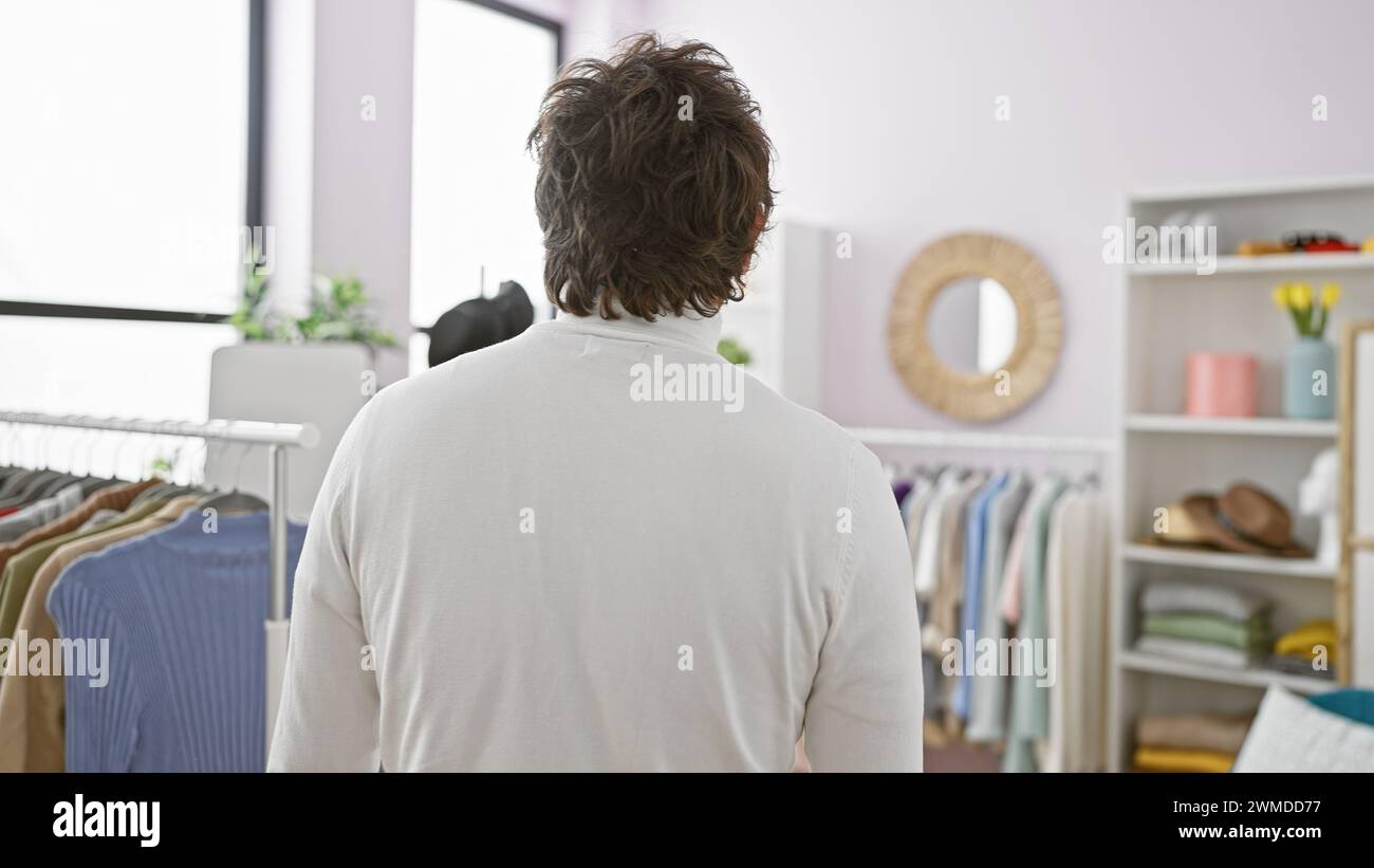 Rear view of a young man in a white shirt standing in a tidy, well-lit ...