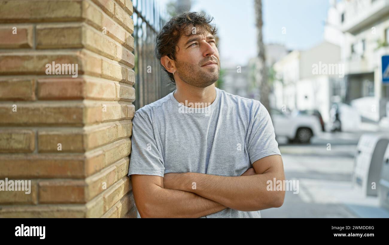 Cheerful young man, standing on an urban street, flashing a confident ...