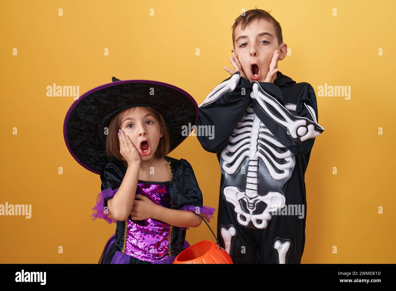 Amazed brother and sister in halloween costumes, mouth open in ...