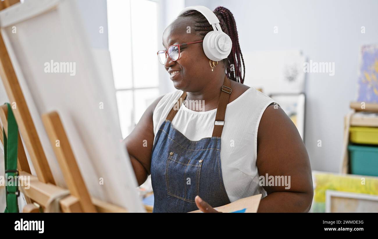 Confident african american woman artist drawing with passion, listening ...