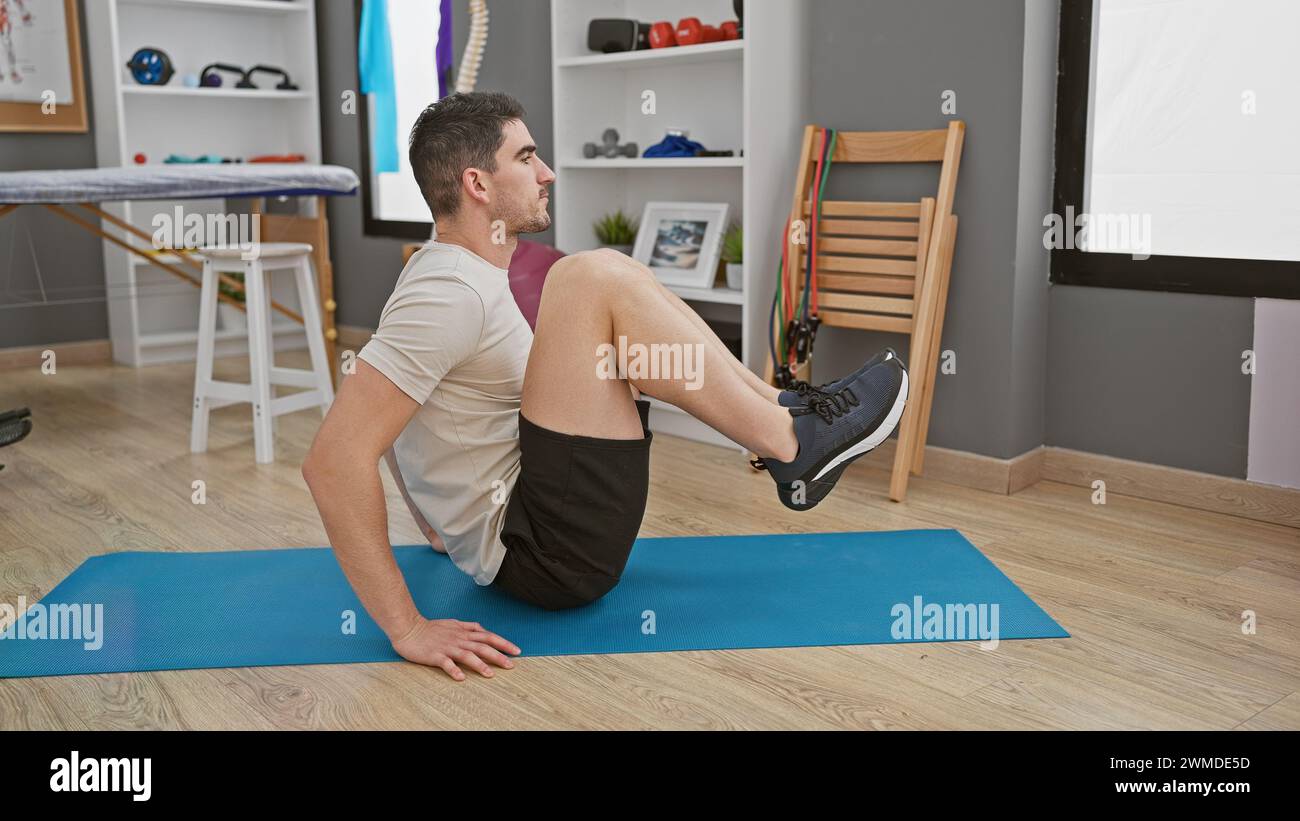 Hispanic man exercising indoors on a blue mat inside a modern ...
