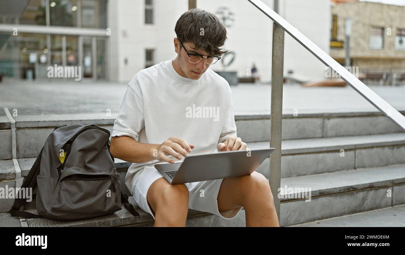 Cool hispanic teenager, a smart university student, sits on urban ...