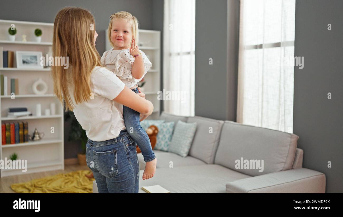 Cheerful mother confidently holding her smiling daughter in her arms ...