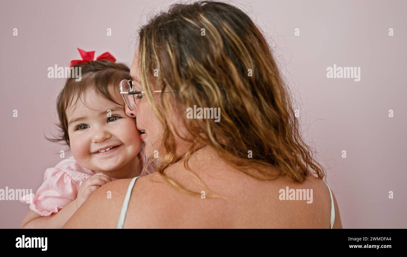 Confident mother showering her lovely daughter with kisses over an ...