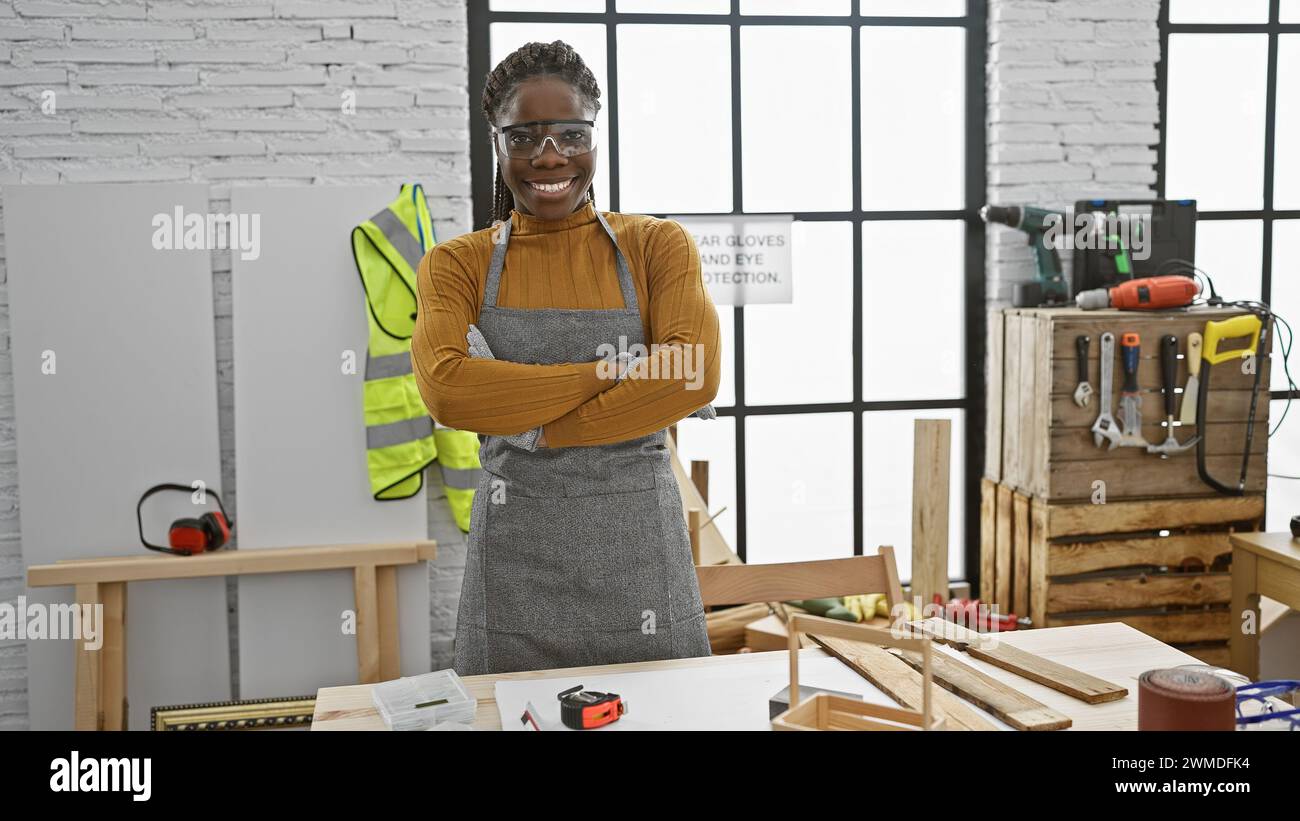 Smiling black woman with braids wearing safety glasses in a carpentry ...