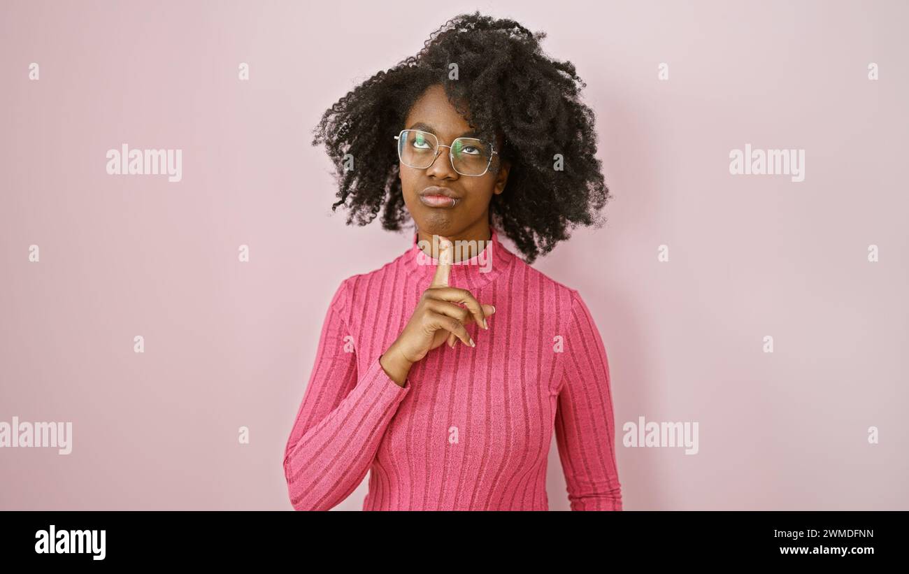 A thoughtful african american woman in glasses stands indoors with a ...