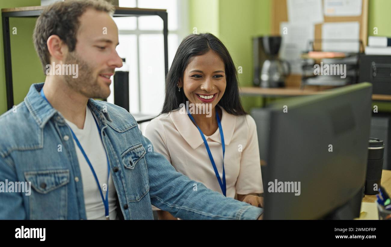 Two workers man and woman sitting on table using computer speaking at ...