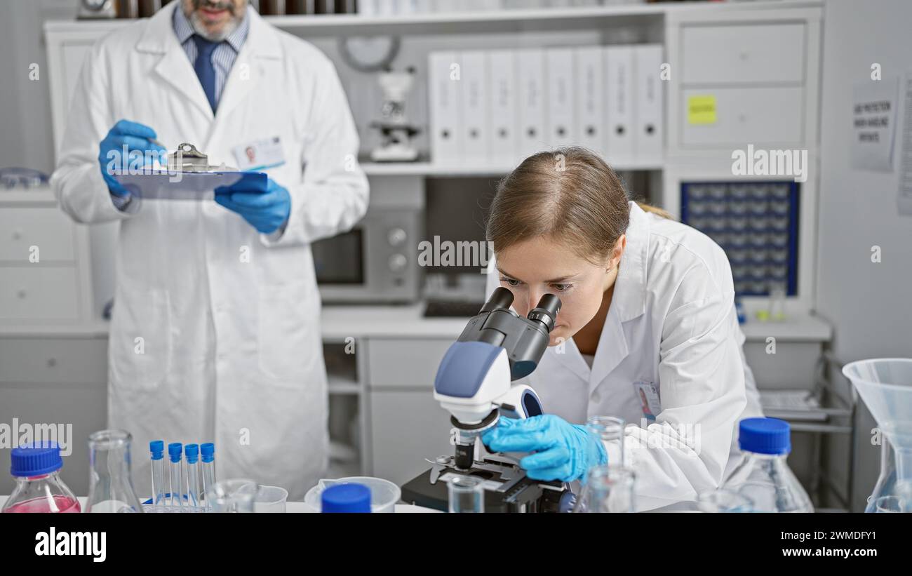 Two serious scientists together in their lab; man and woman partners working on research ...