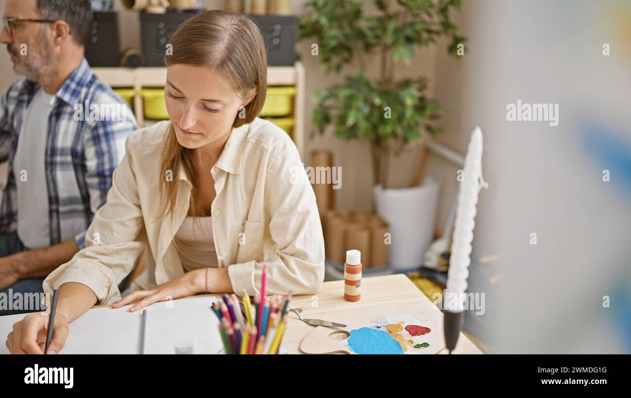 Two focused artists, a woman and man, drawing on canvas and paper ...