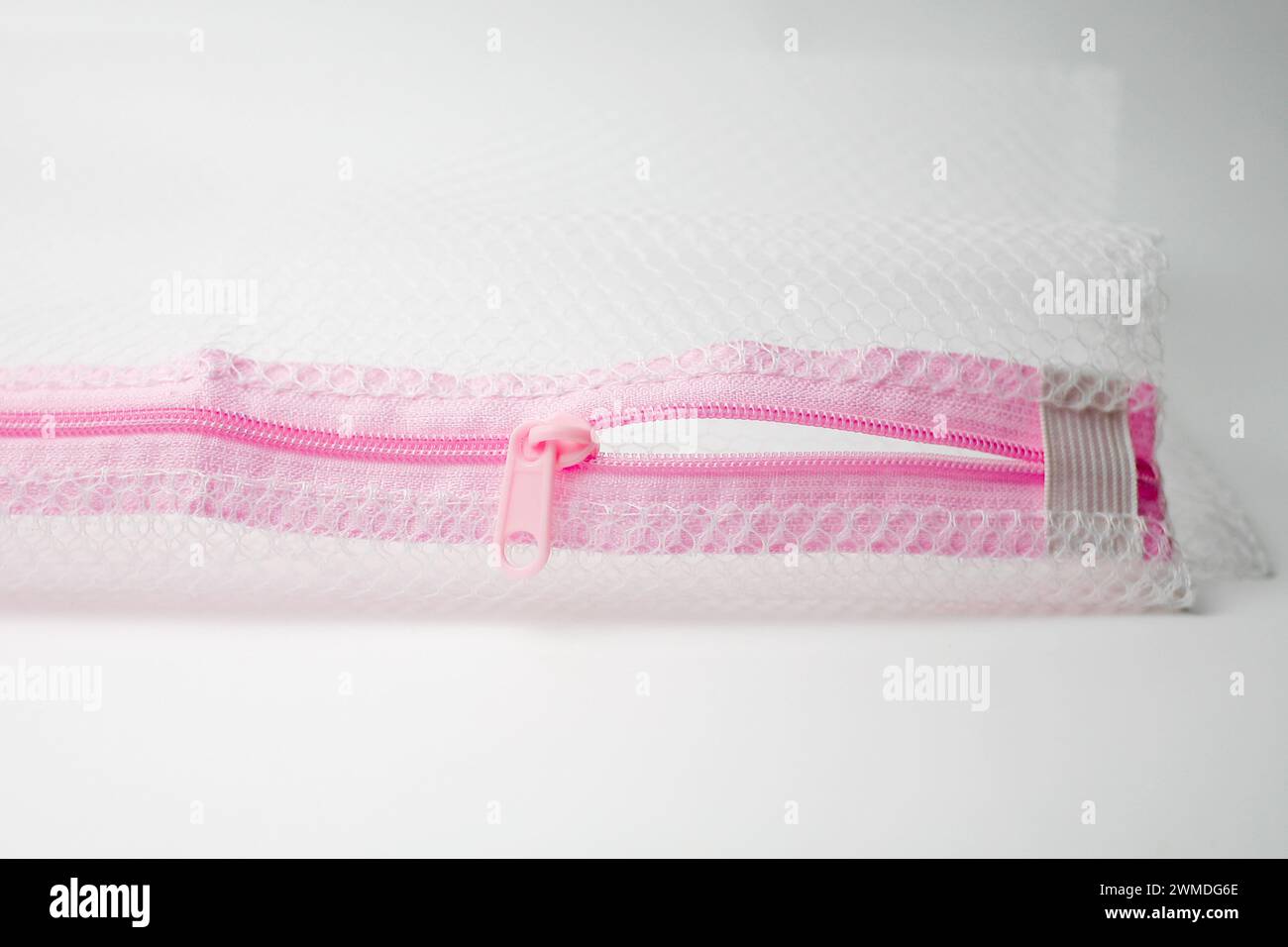 Close up half open pink zipper on mesh fabric isolated on white ...