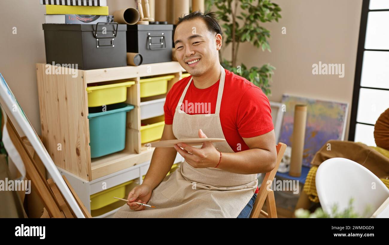 Confident young chinese man happily engulfed in the world of art ...