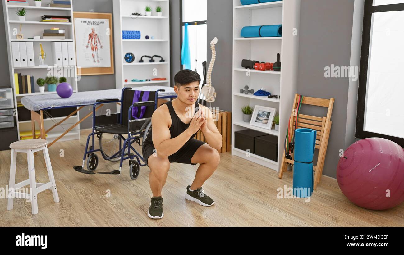 Young asian man doing squats in a well-equipped physiotherapy clinic ...