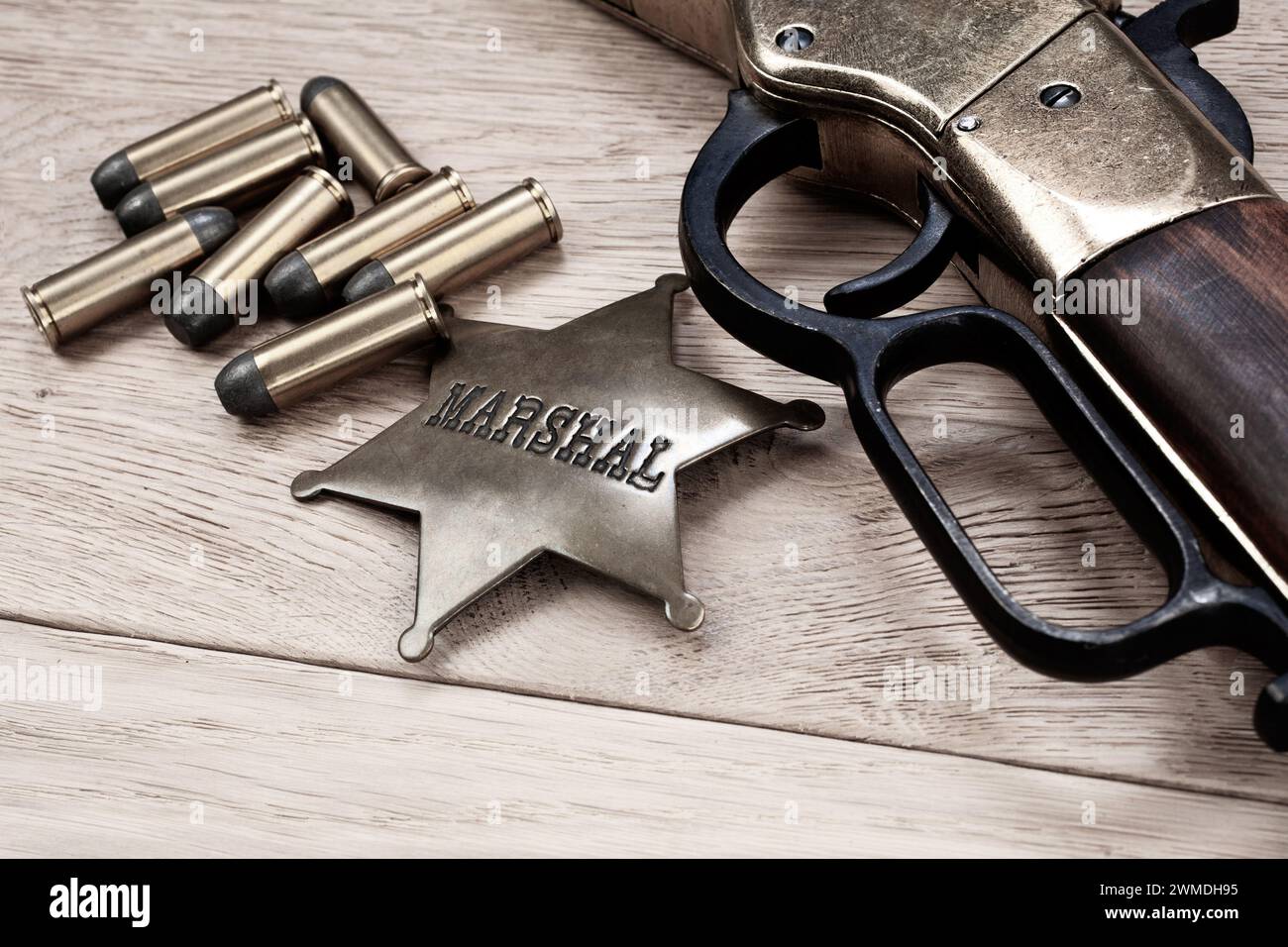 Old west lever action rifle with ammunition and marshal badge on wooden ...
