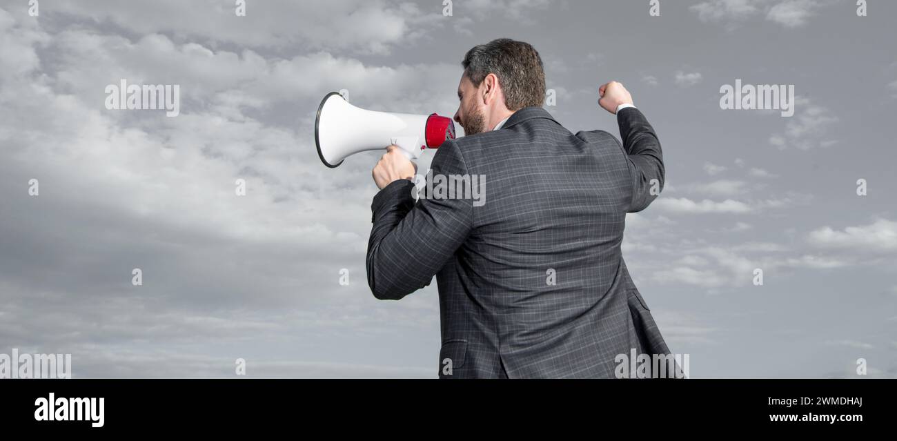 back view of businessman shout in loudspeaker on sky background ...