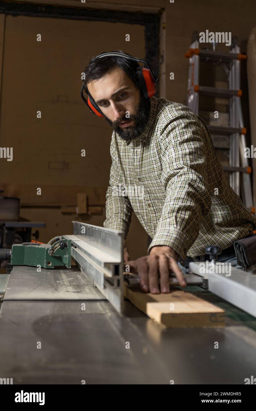 Vertical photo a concentrated carpenter a with ear protection uses a ...