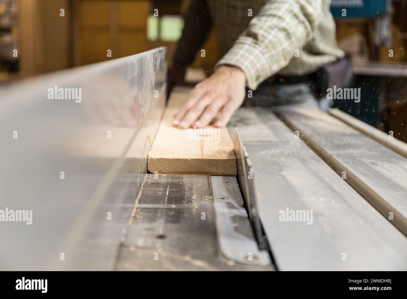 Horizontal photo close-up of a woodworker's hands as they guide a piece ...
