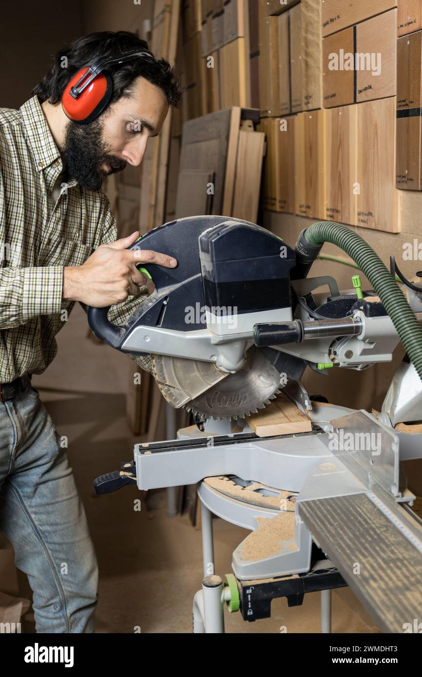 Vertical photo A focused carpenter is seen cutting a wooden plank with ...