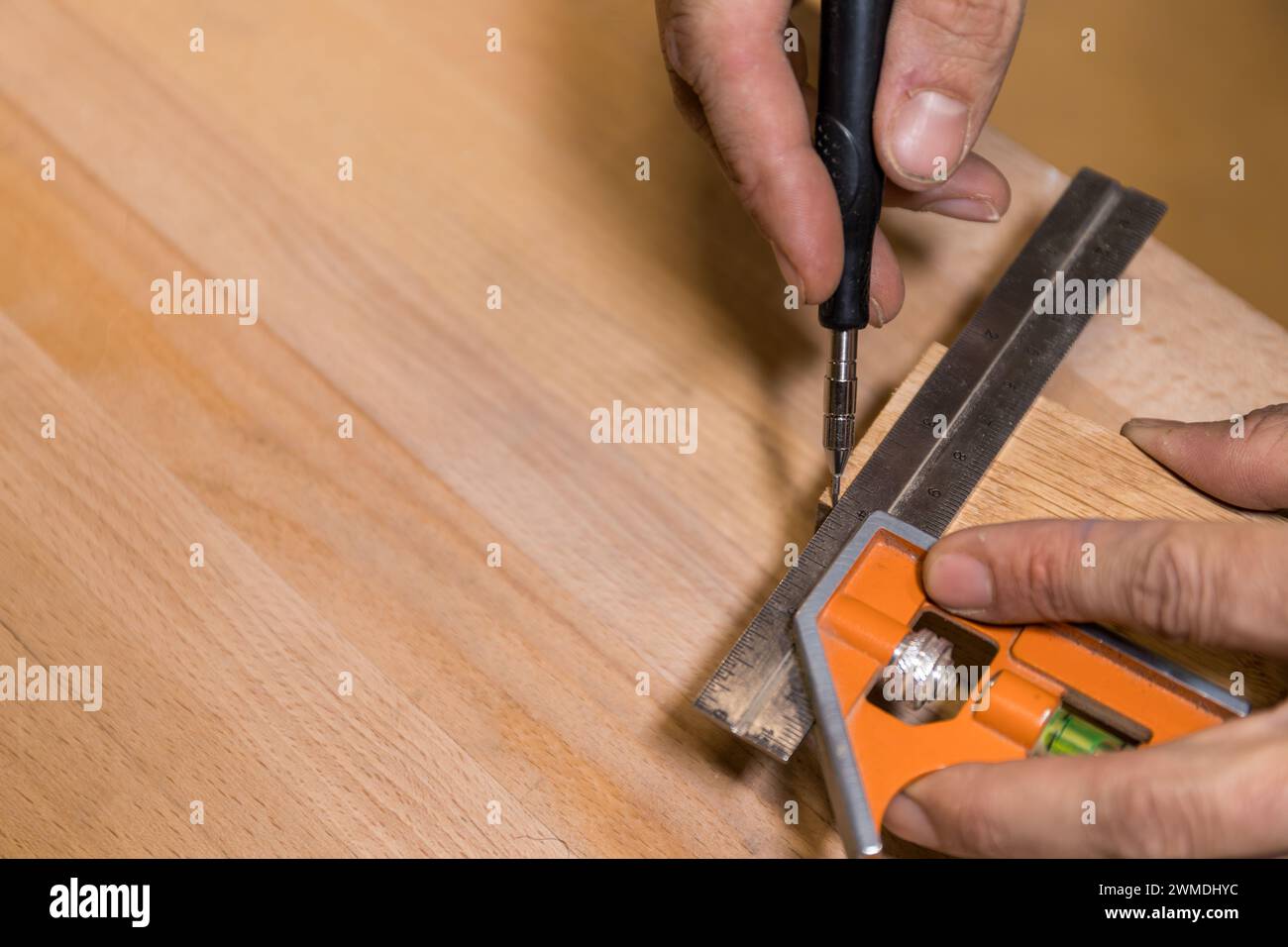 Horizontal photo Craftsman's hands are shown marking a wooden plank ...