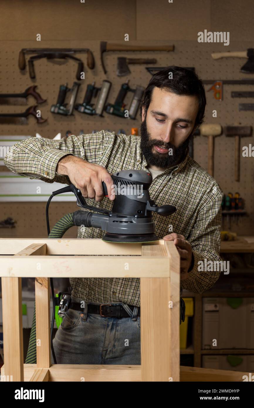 Vertical photo Dedicated carpenter in the process of sanding a wooden ...