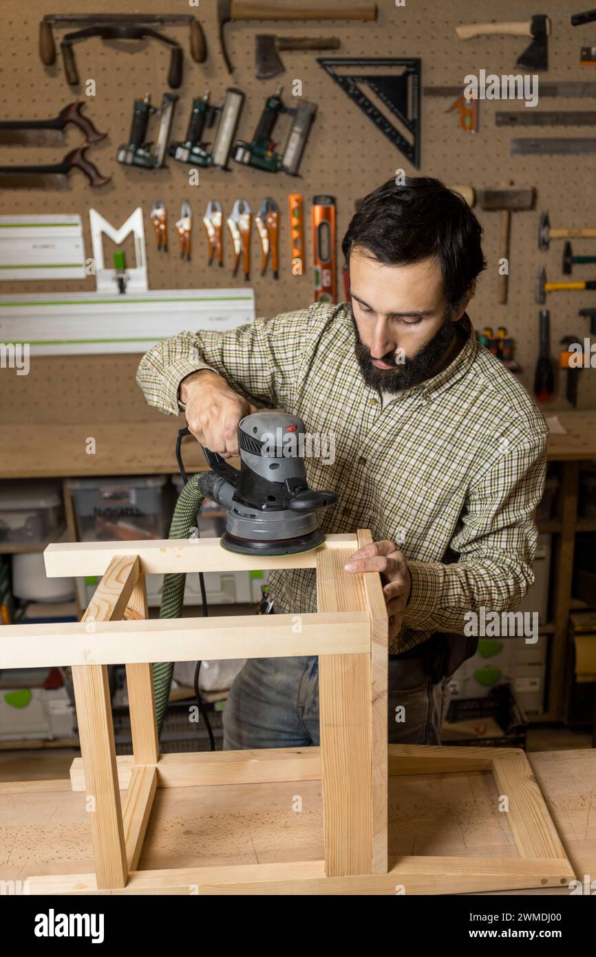 Vertical photo concentrated craftsman in the process of sanding a ...