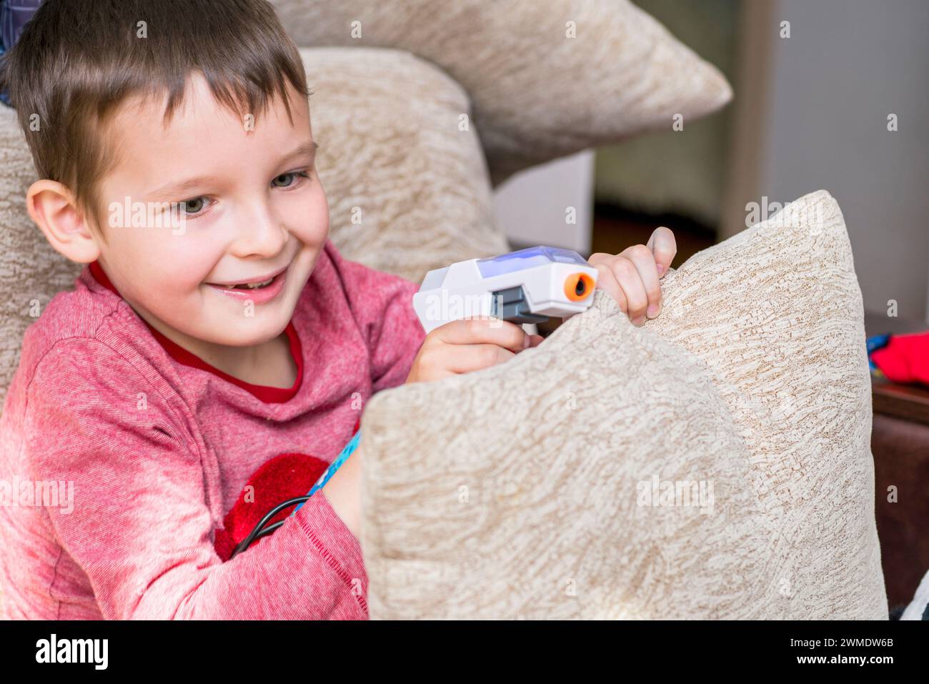 Cute boy is playing with toy guns at home Stock Photo - Alamy