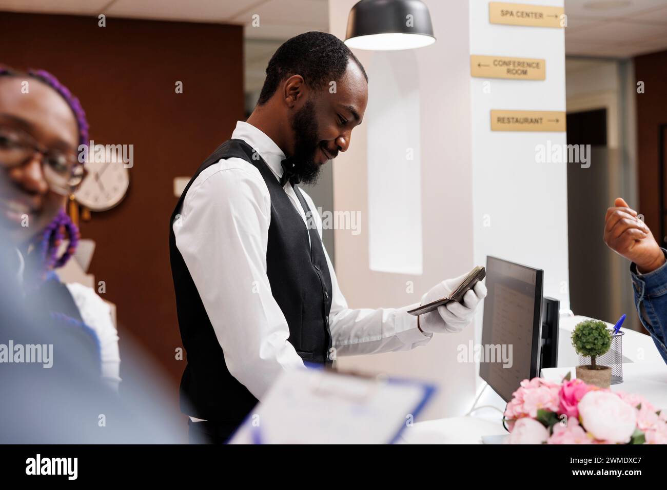 Smiling friendly African American man receptionist checking tourist ...