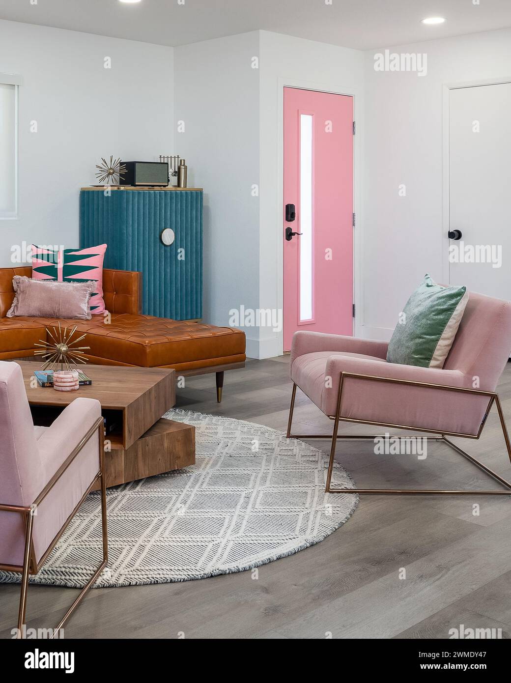Trendy mid-century modern living room with pink chairs, a pink door ...