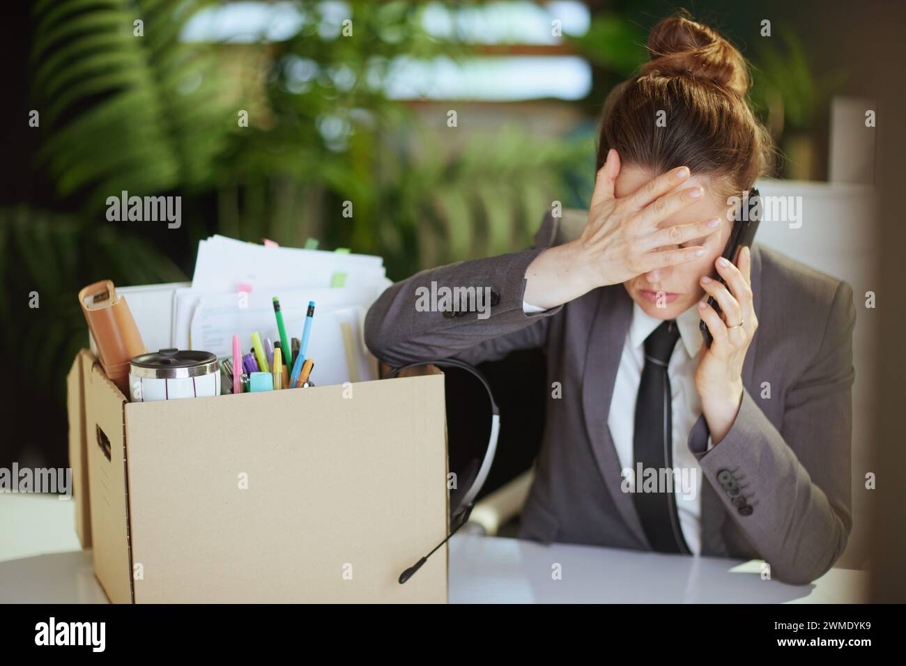 New job. sad modern woman worker in modern green office in grey ...