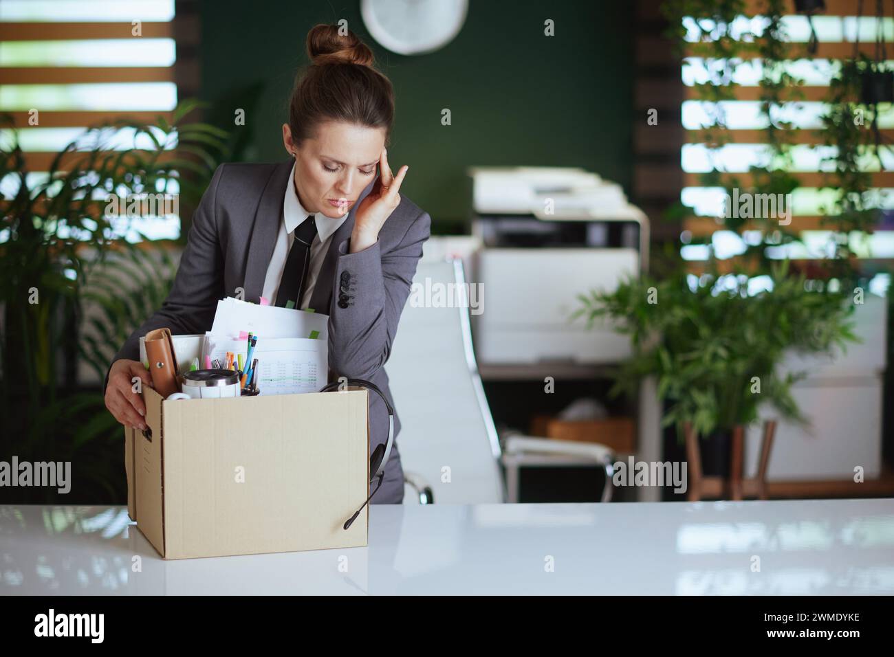 New job. concerned modern woman worker in modern green office in grey ...