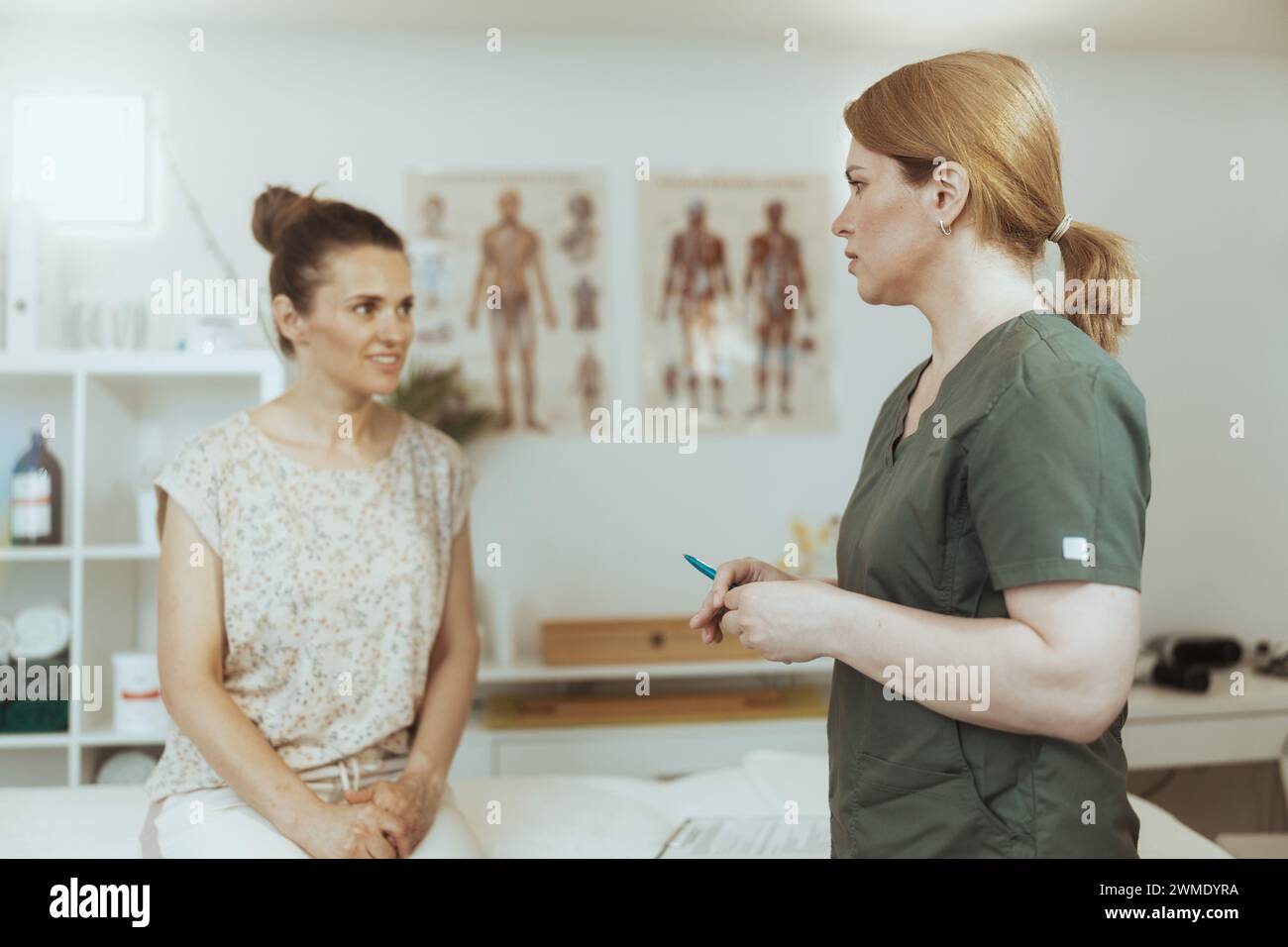 Healthcare time. massage therapist woman in massage cabinet with client doing checkup Stock ...
