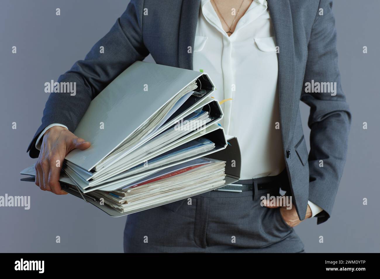 Closeup on business woman in grey suit with folders isolated on grey ...