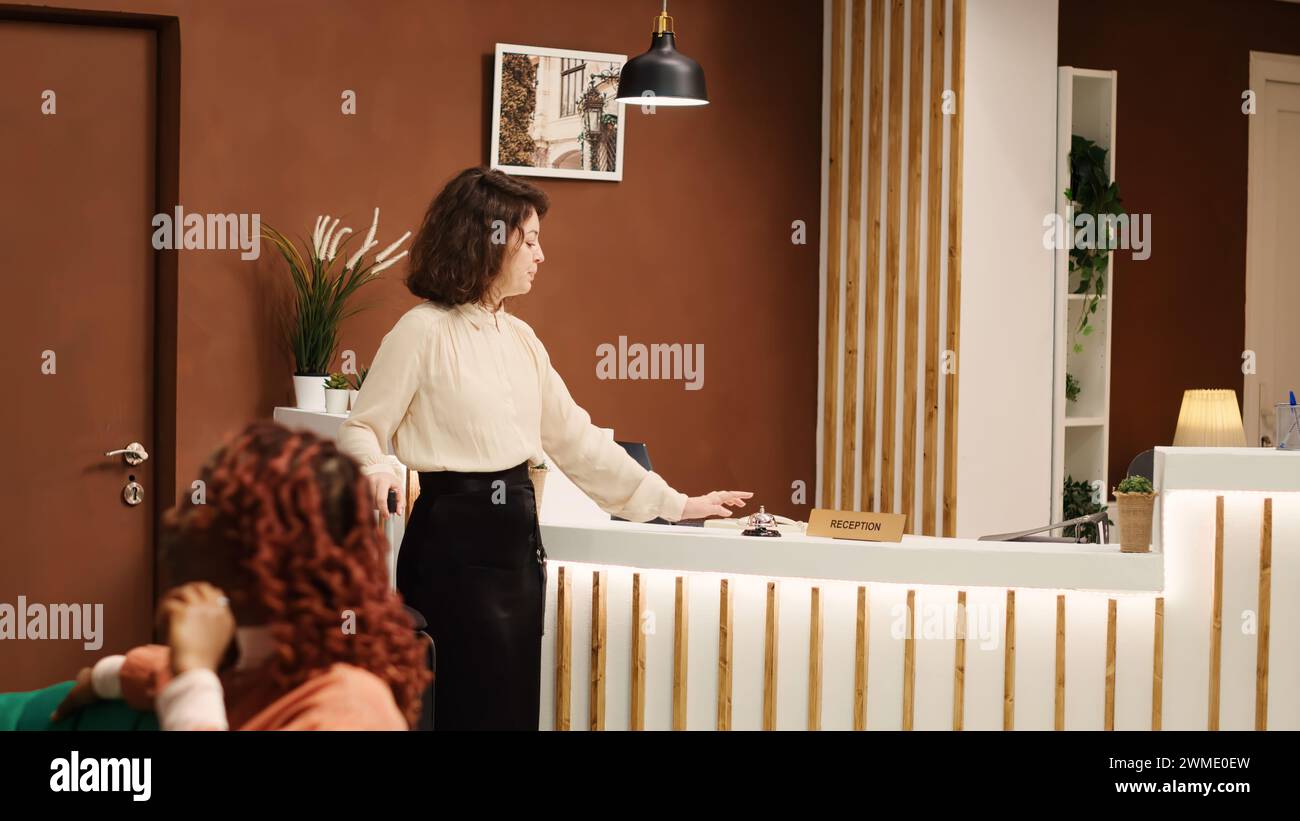 Friendly hotel personnel helping guest with room booking check in ...