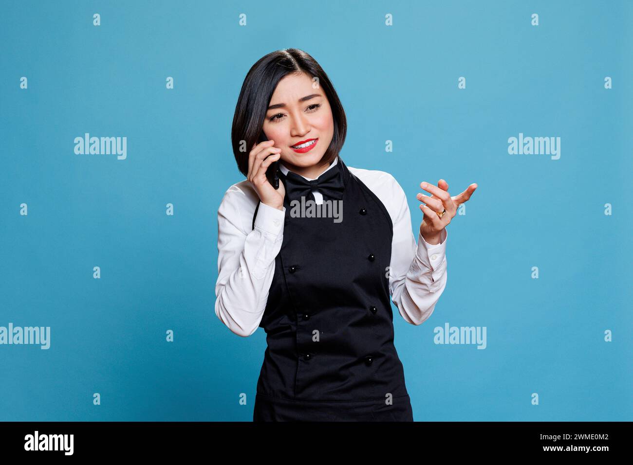 Cafe waitress smiling while managing conversation with client on mobile ...