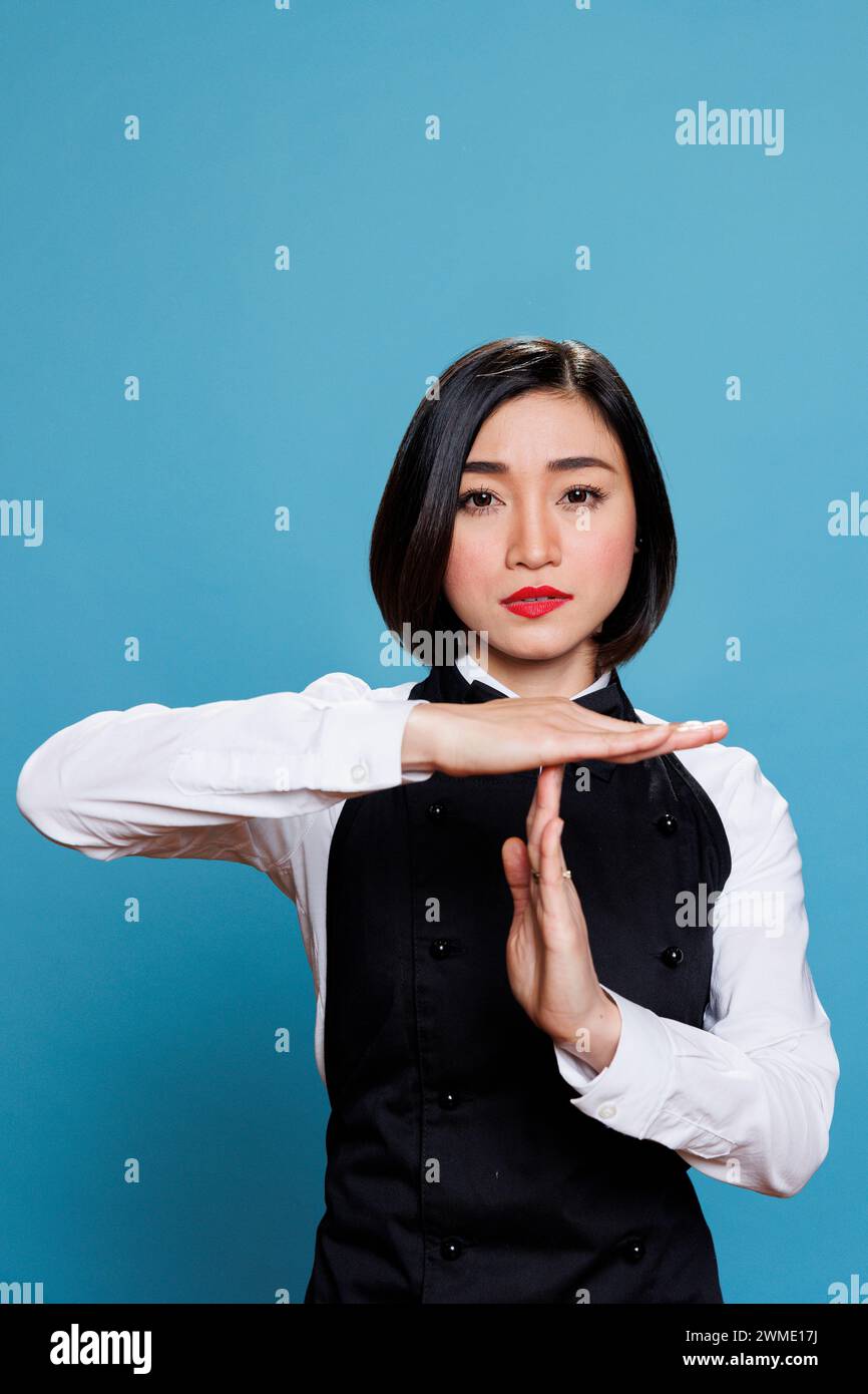 Serious asian waitress in uniform showing timeout sign with hands ...