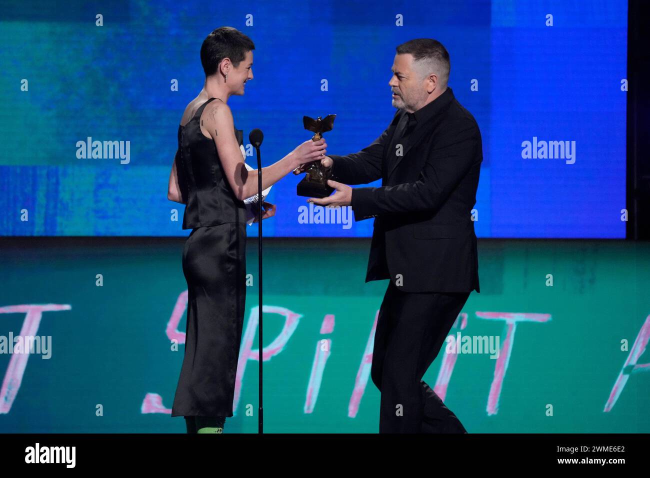 Emma Corrin, left, presents the award for best supporting performance ...